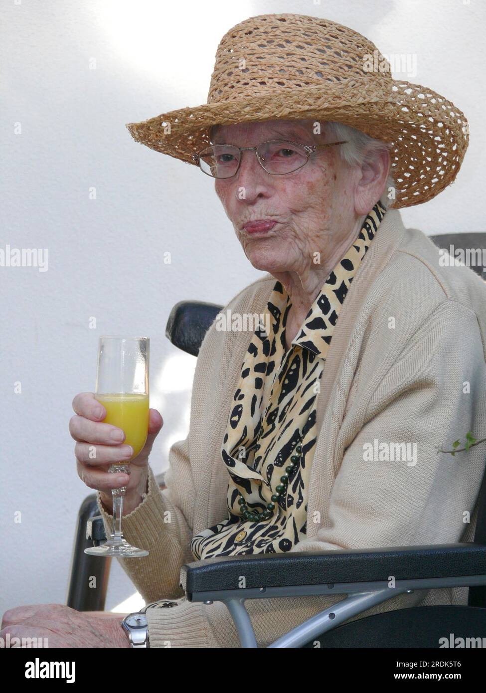 Old woman 95 years old, portrait with orange juice in champagne glass ...