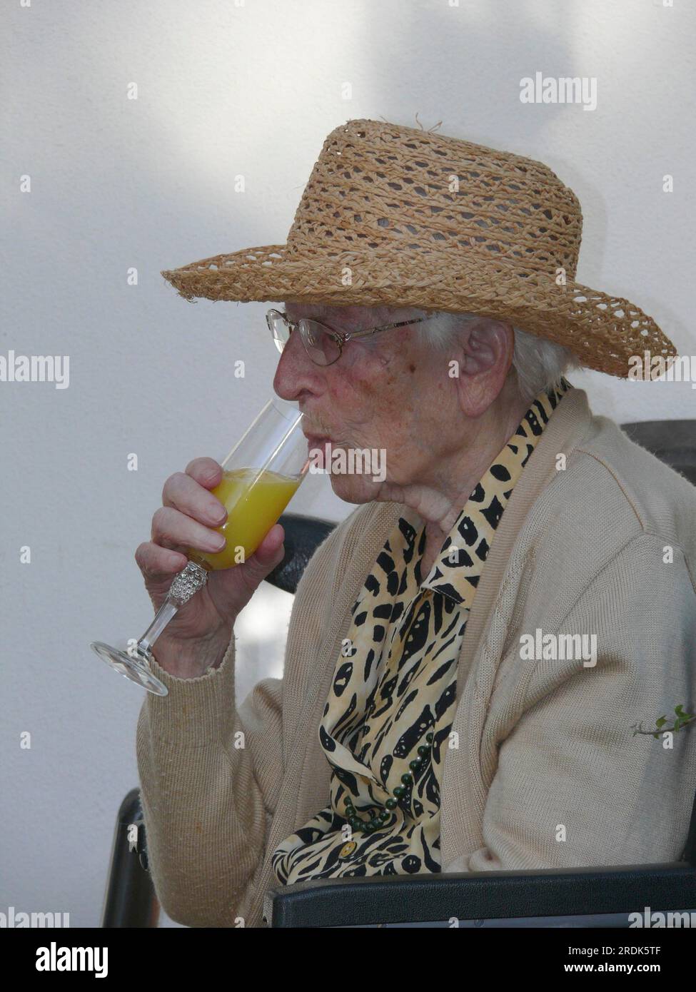 Old woman 95 years old, portrait with orange juice in champagne glass ...