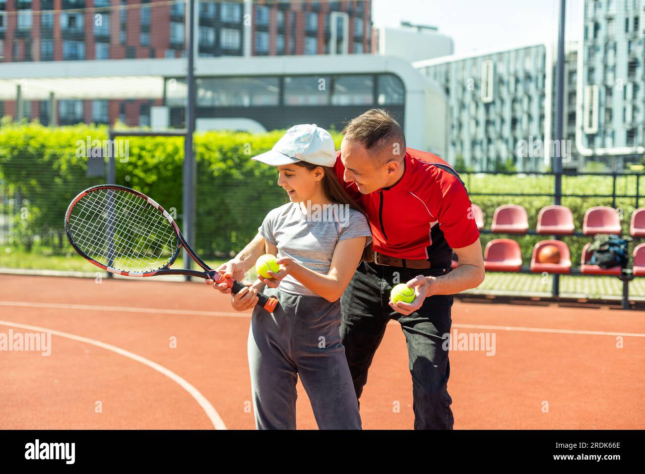 Father is a tennis coach for his daughter. Female child is playing in ...