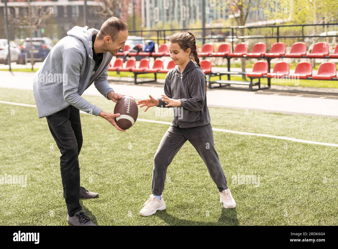 girl holding an oval brown leather rugby ball and smiling while playing ...