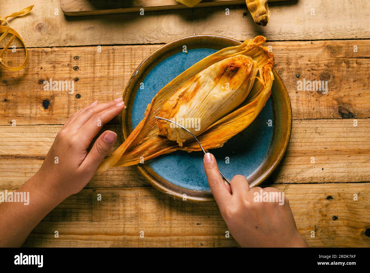 Hands of a person cutting a tamale with a fork. Tamale, typical Mexican ...