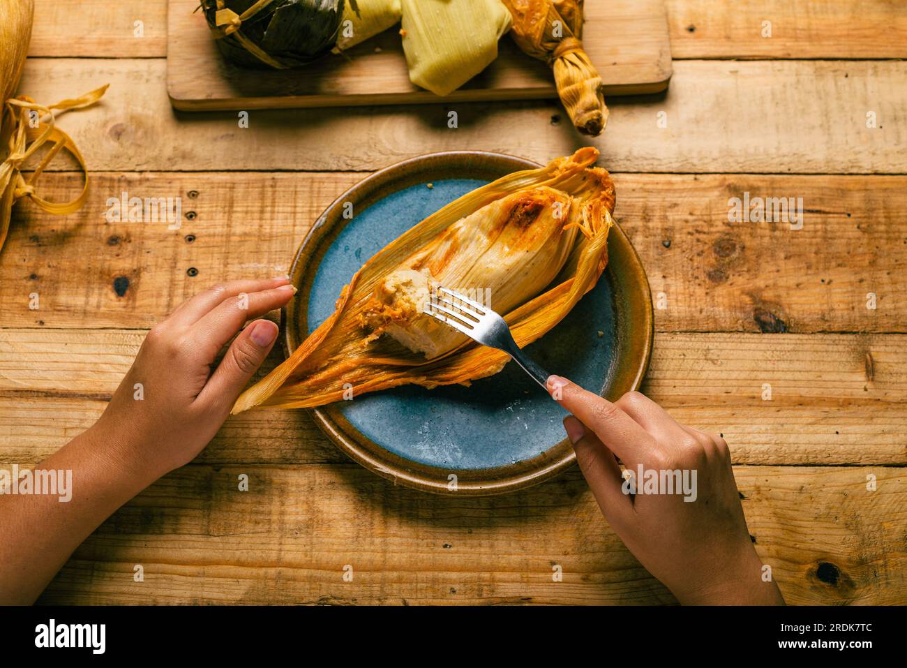 Hands of a person cutting a tamale with a fork. Tamale, typical Mexican ...