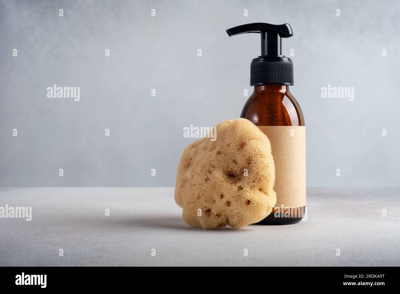 Mock up brown glass bottle and sea natural sponge on a gray background ...