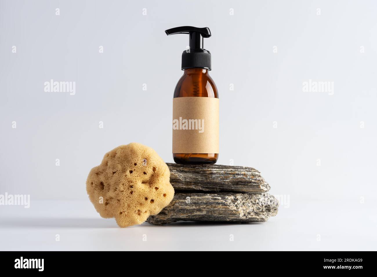 Mock up brown glass bottle and sea natural sponge on a stone podium on ...