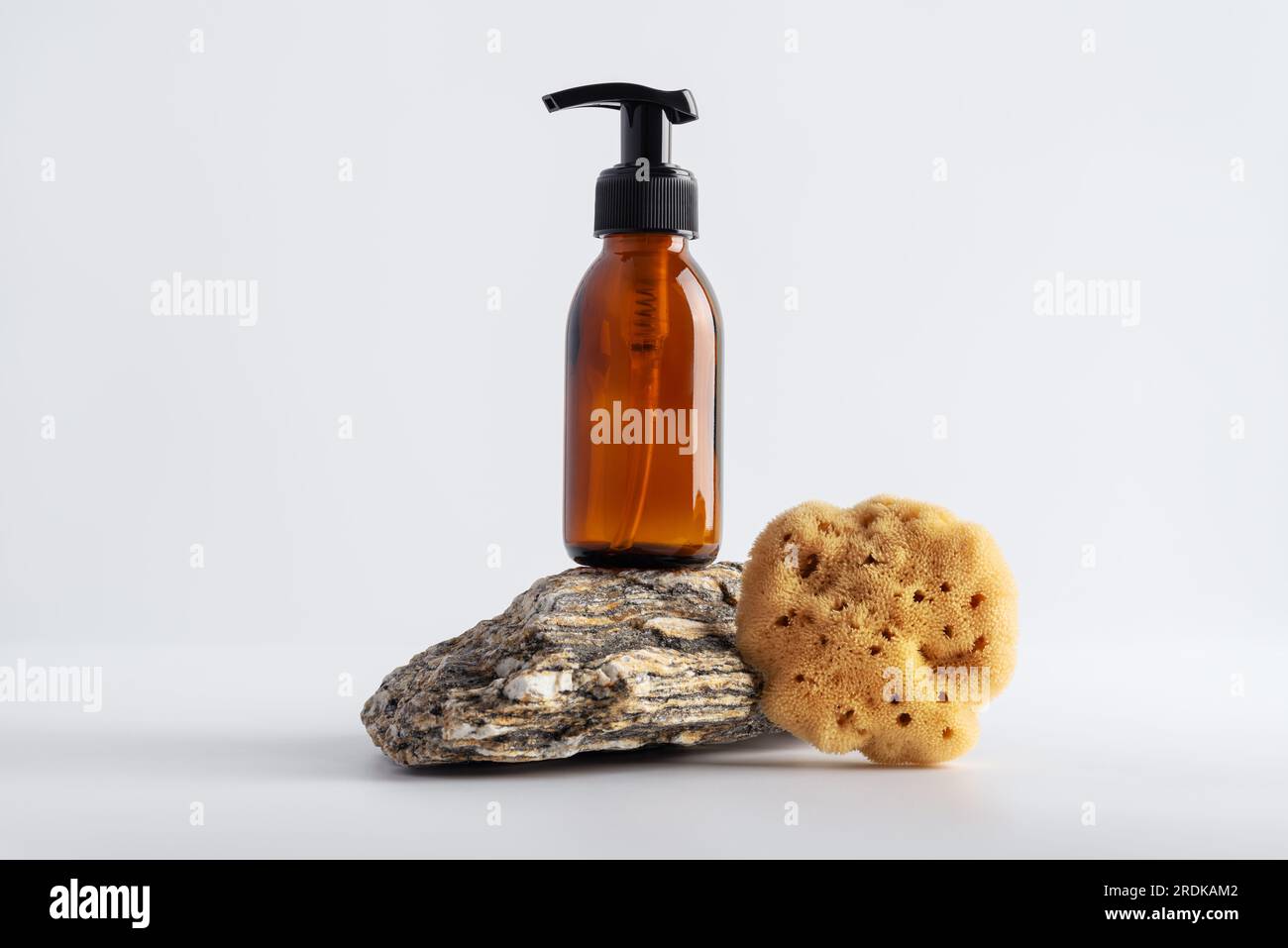 Mock up brown glass bottle and sea natural sponge on a stone podium on ...