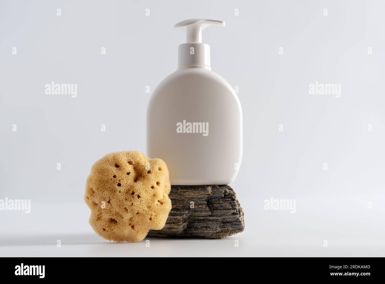 Mock up white plastic bottle and natural sea sponge on a stone podium ...