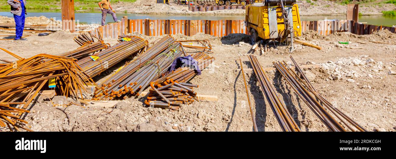 Installed metal piles along river bank, build in for bridge foundation ...