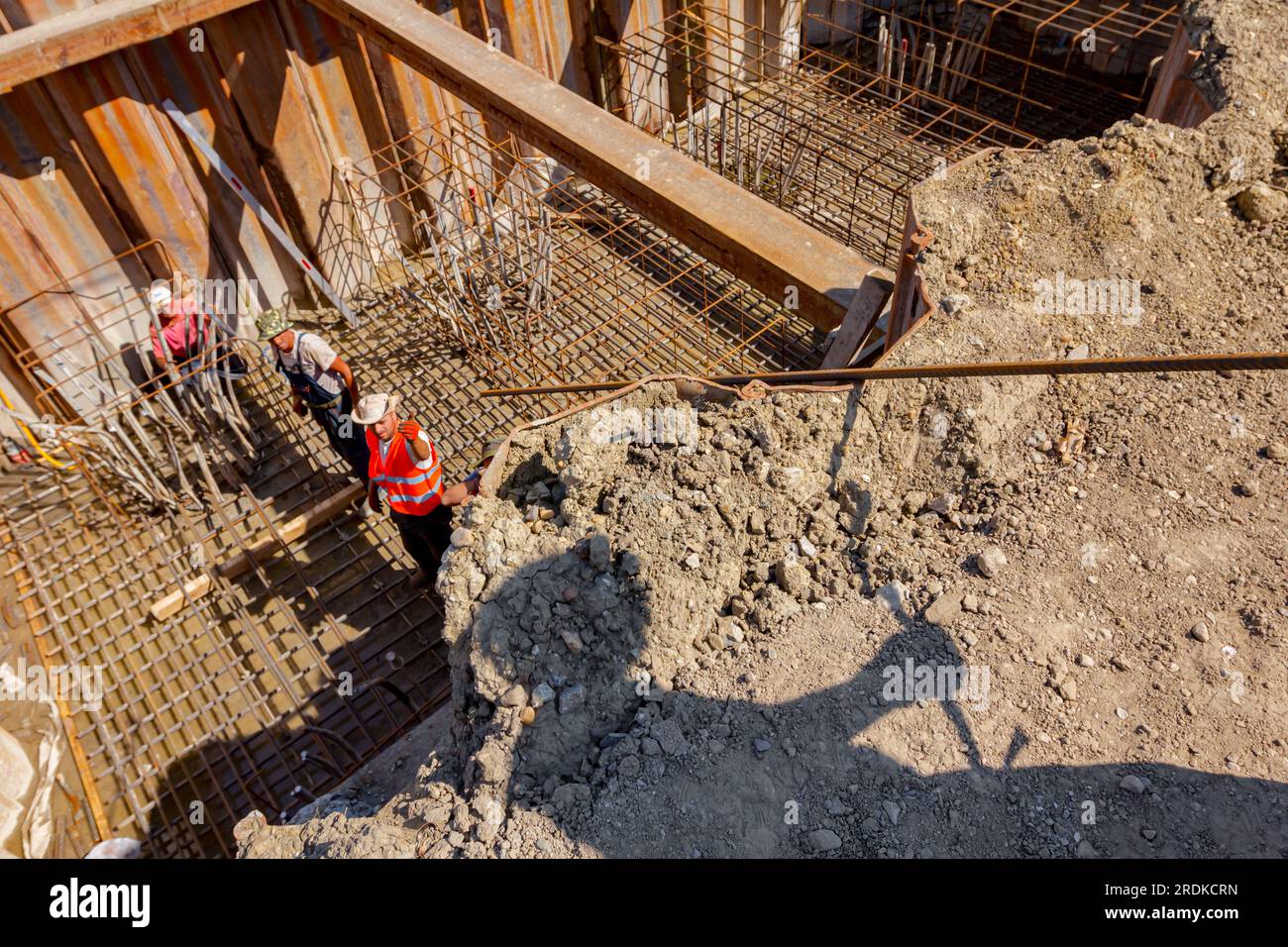 Silhouette of worker, master in shadow gives reinforcing rod to another ... Silhouette of worker, master in shadow gives reinforcing rod to another ...