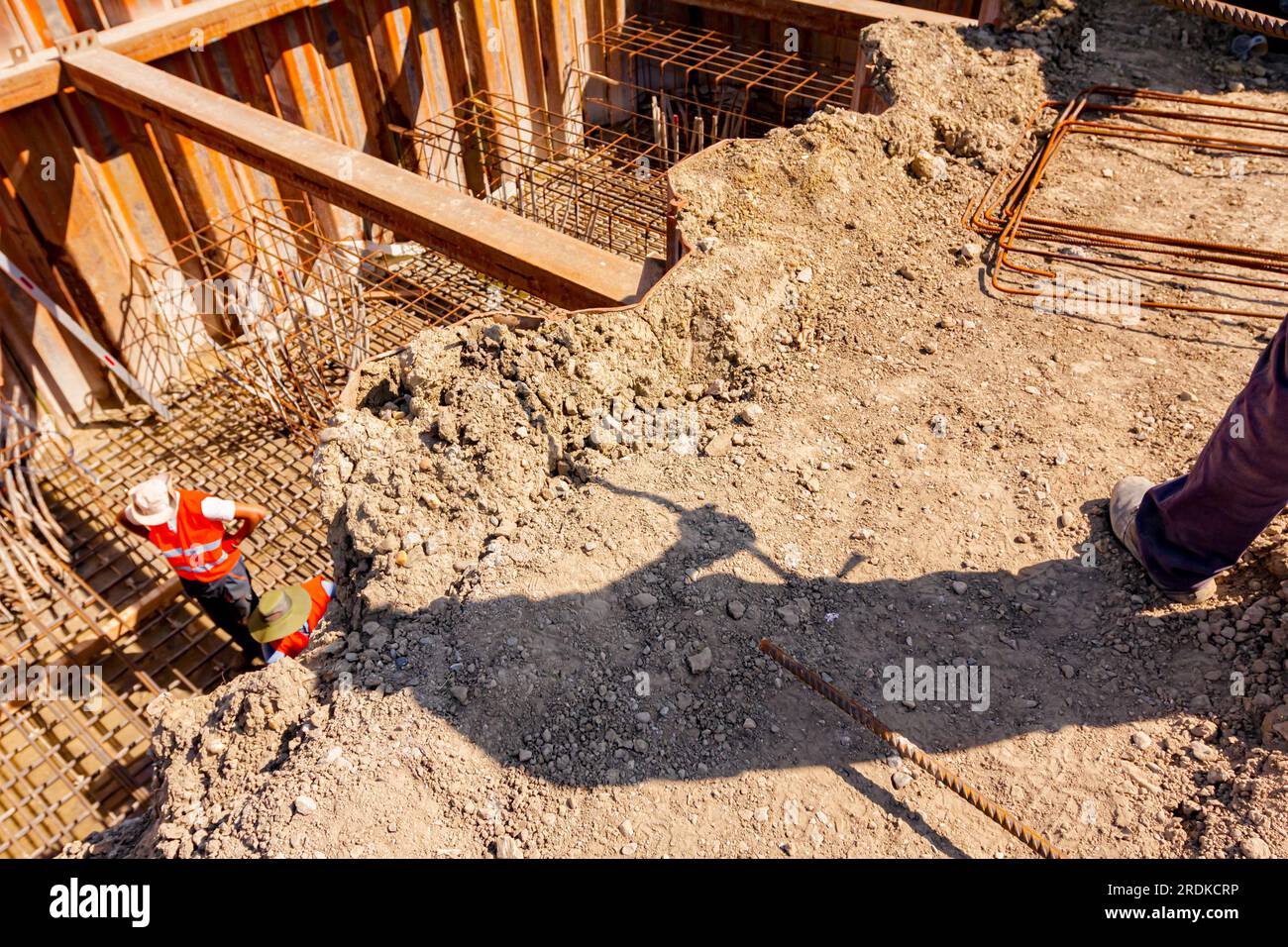 Silhouette of worker, master in shadow gives reinforcing rod to another ... Silhouette of worker, master in shadow gives reinforcing rod to another ...