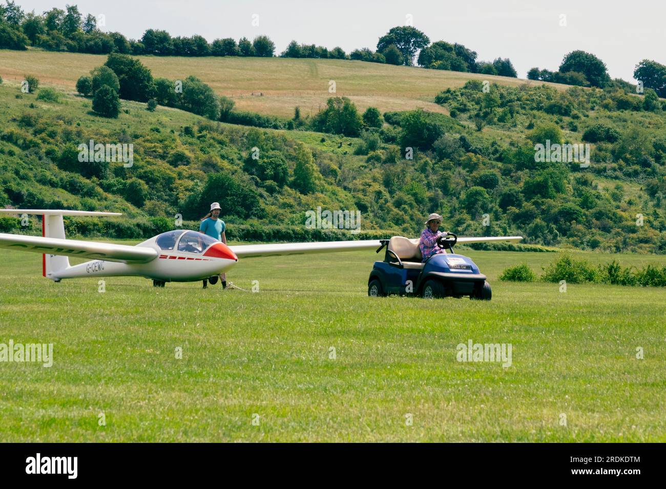 A person pulls a glider along the ground with a golf cart at an ...