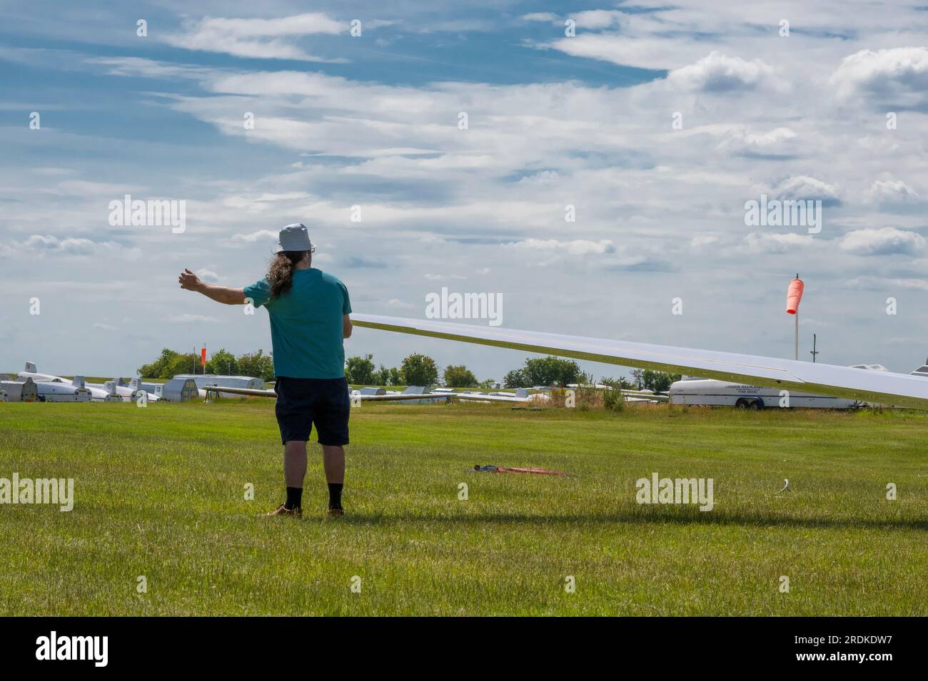 A man holds the wing of a glider while it waits to be towed along the ...