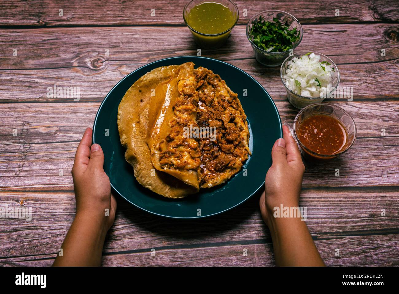 Hands of a person preparing a gringa pastor a la diabla accompanied by ...