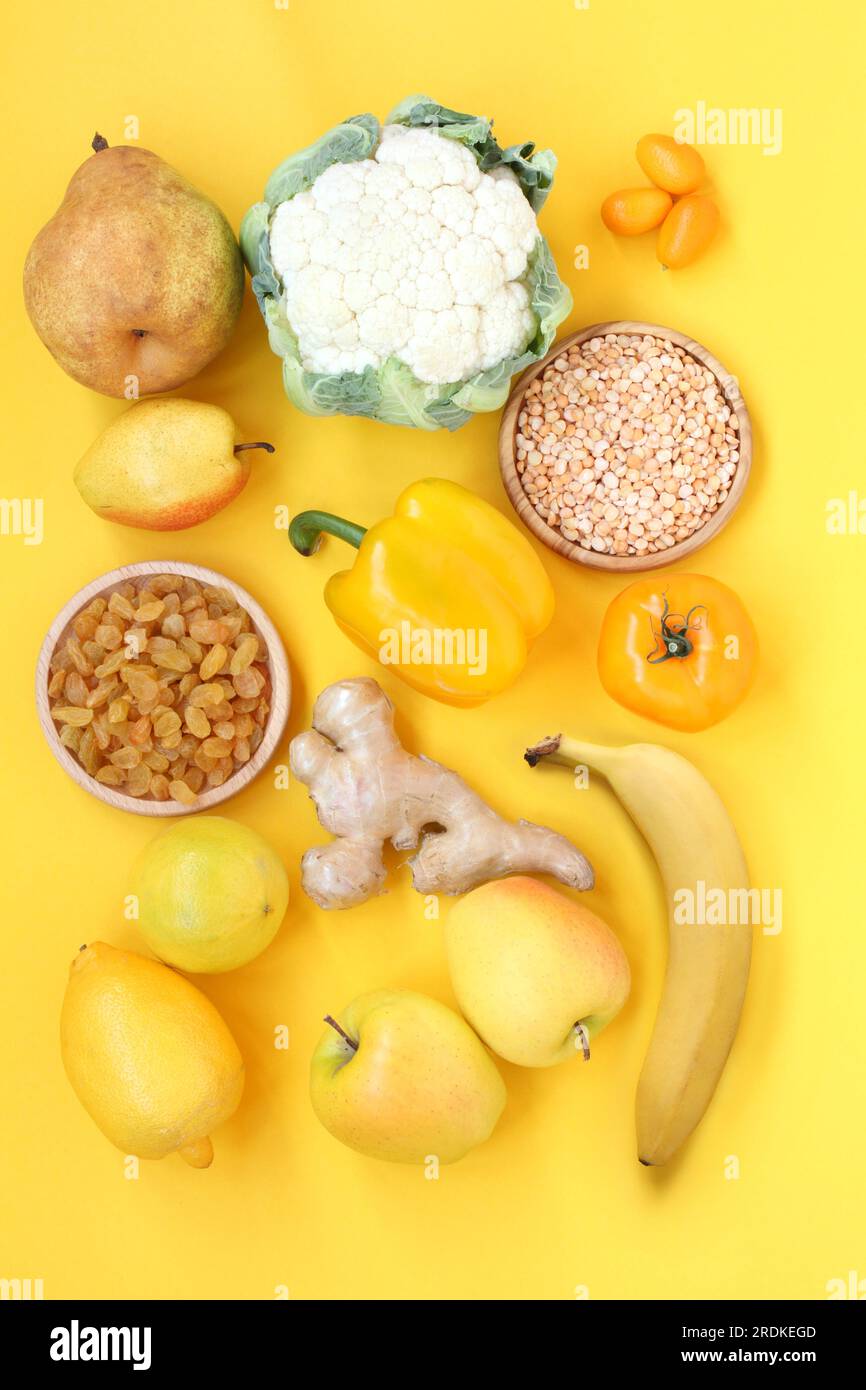 Yellow fruits and vegetables on a yellow background. Pears, raisins ...