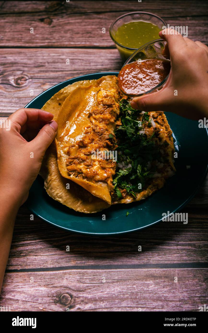 Hands of a person preparing a gringa pastor a la diabla accompanied by ...