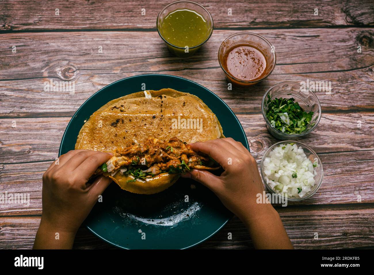 Hands of a person preparing a gringa pastor a la diabla accompanied by ...