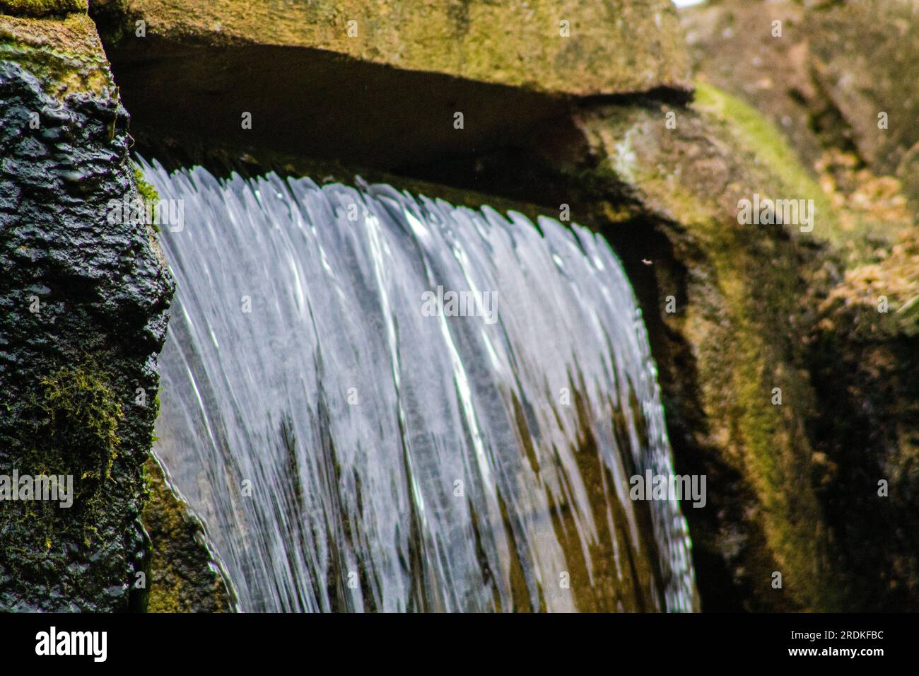 Detail of a small waterfall flowing down a stone wall in a park Stock ...