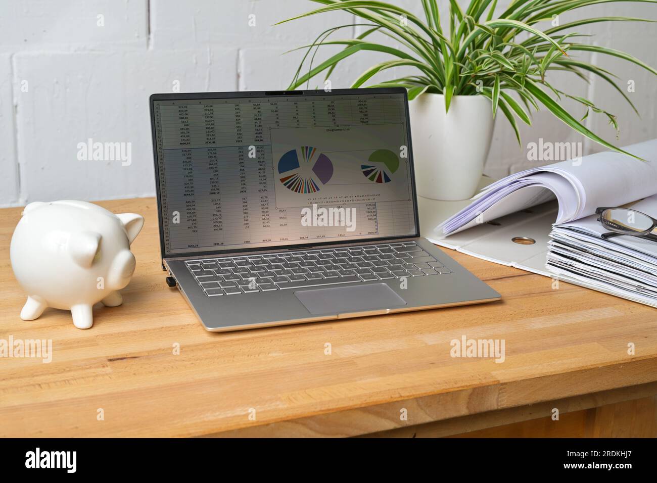Wooden desk with laptop and number charts on the screen, piggy bank and ...