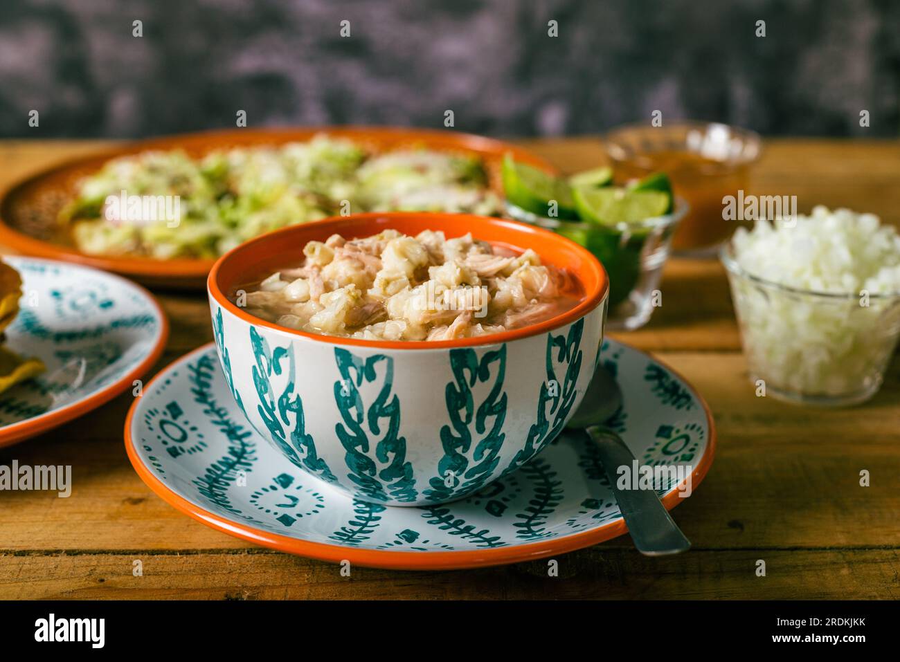Pozole served in a deep dish, with salsa and vegetables on a wooden ...