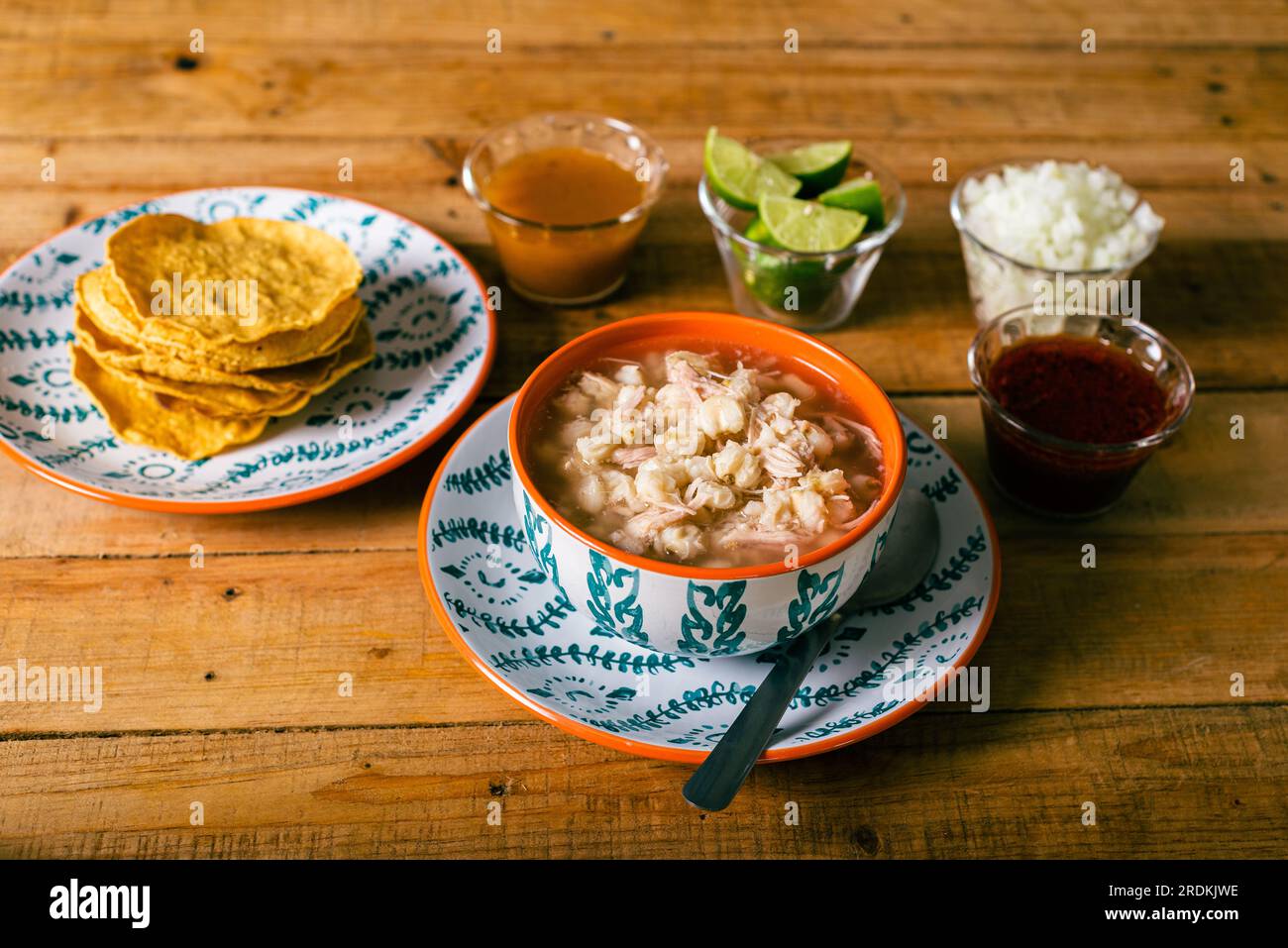 Pozole served in a deep dish, with tostadas, salsa and vegetables on a ...