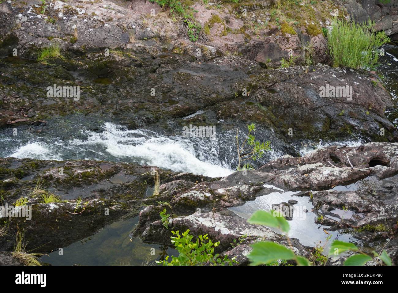a small waterfall over a rocky cliff Stock Photo - Alamy