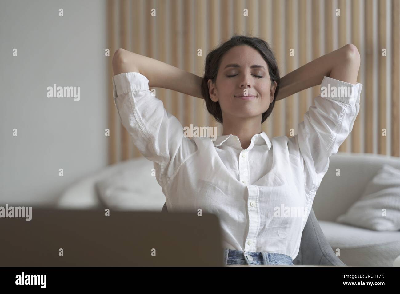 Attractive positive young female entrepreneur sitting at desk at home ...