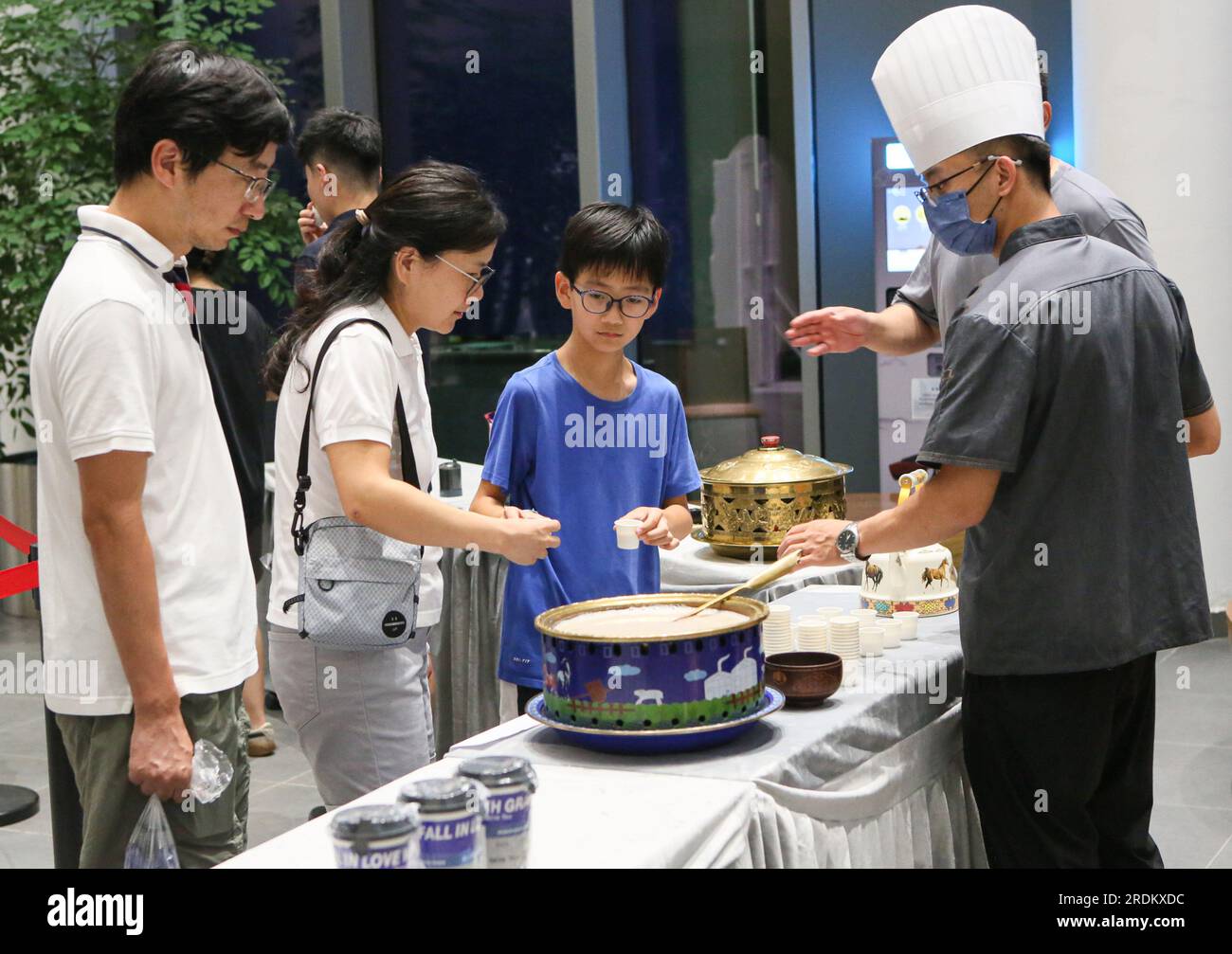 Shanghai. 21st July, 2023. Visitors taste tea with milk at a night fair ...