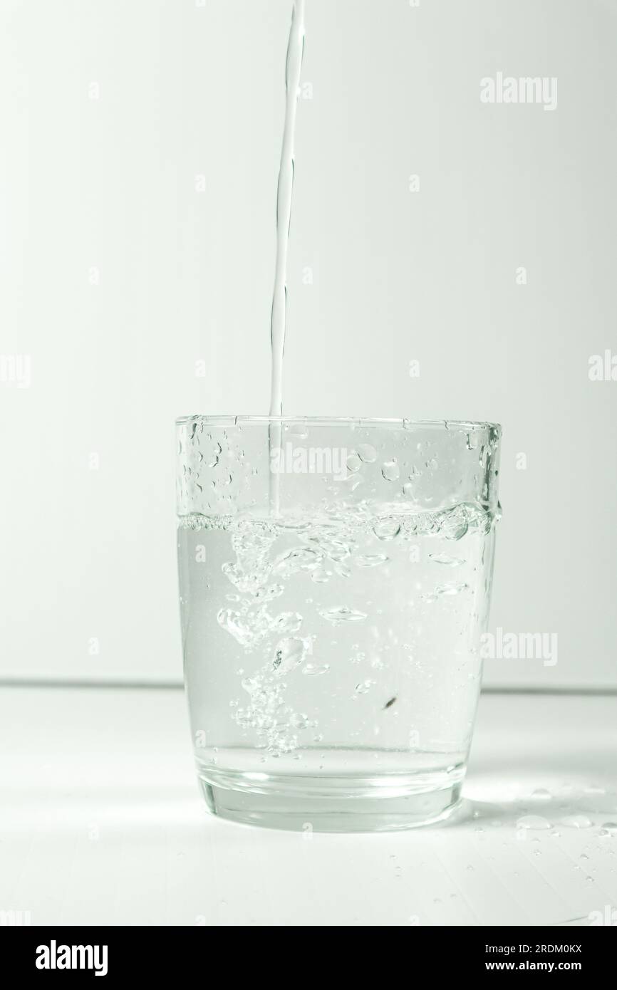 Water pouring into glass on white background Stock Photo - Alamy