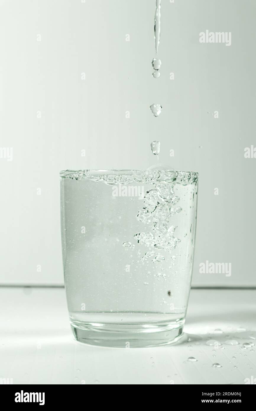 Water pouring into glass on white background Stock Photo - Alamy