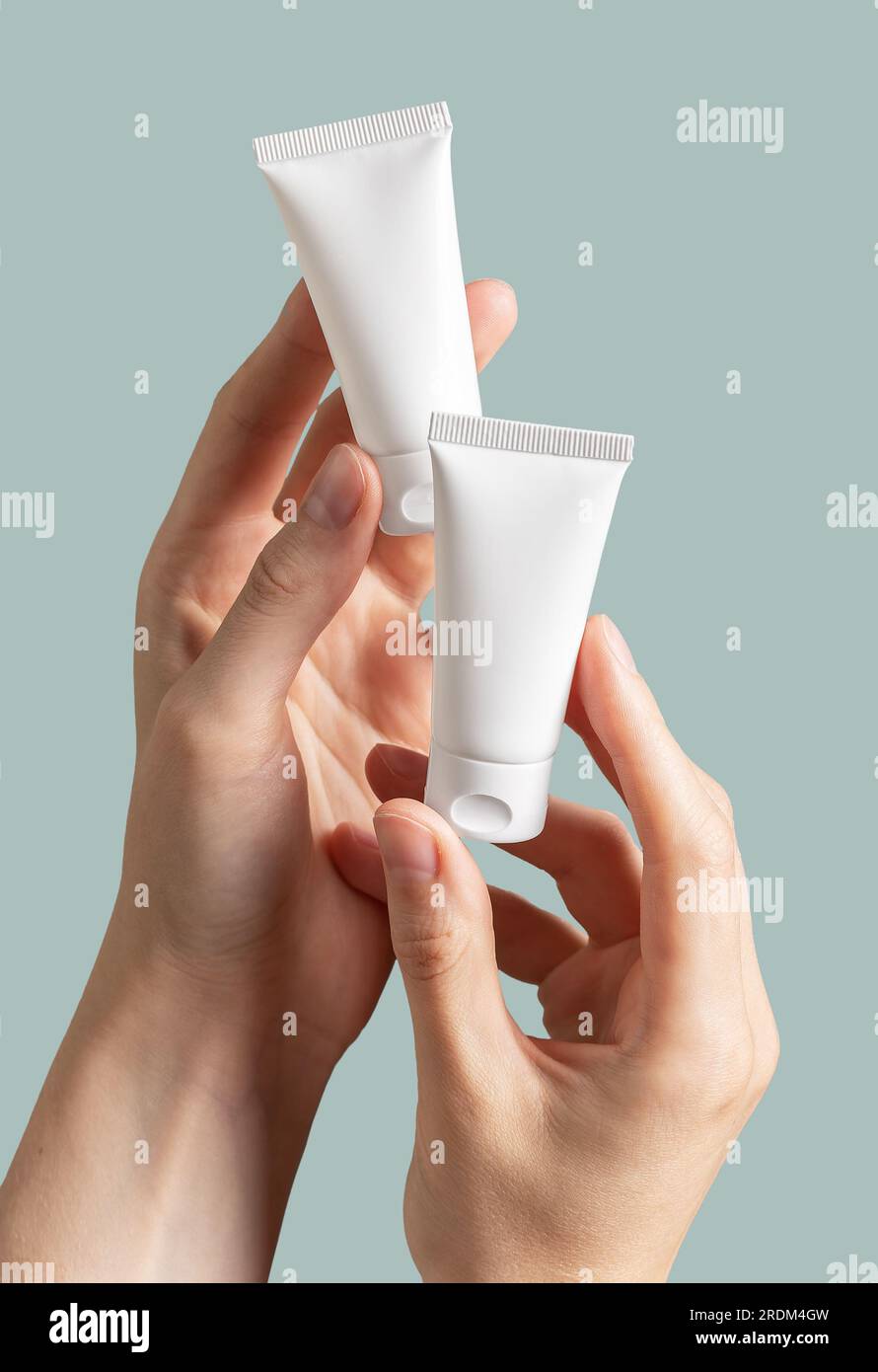 Hand holding two small cream tubes mock-ups Stock Photo - Alamy