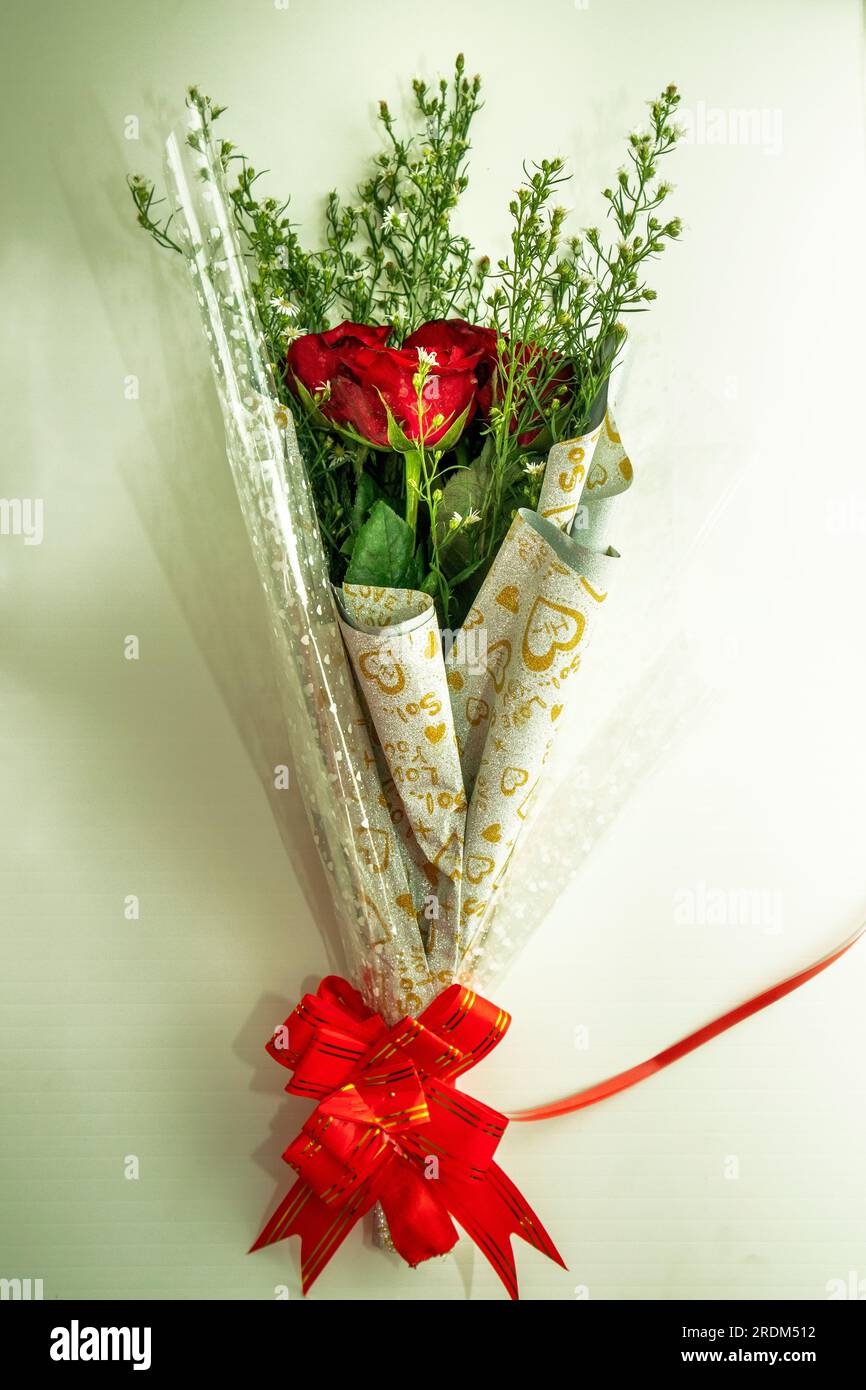 bouquet of red roses and green leaves with a red ribbon Stock Photo - Alamy