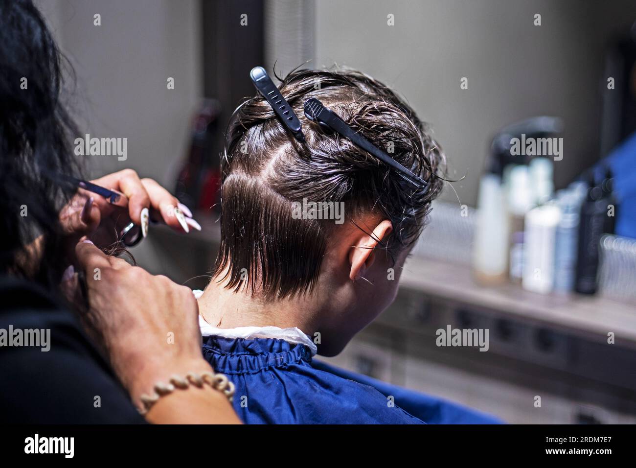 female barbeshoper cuts the back of the hair with a comb for a teenage ...