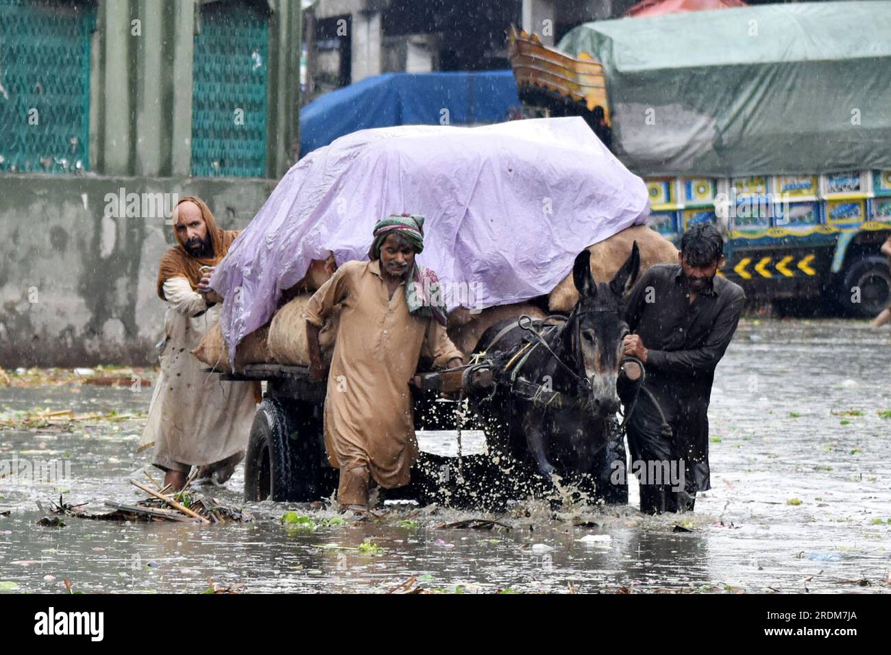 Lahore. 22nd July, 2023. People push a donkey-cart through a flooded road after heavy monsoon ...