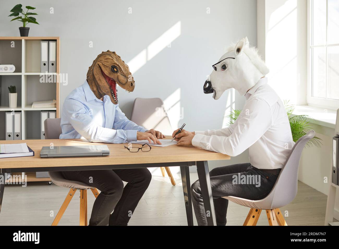 Two funny business men wearing animal masks sitting at their workplace ...