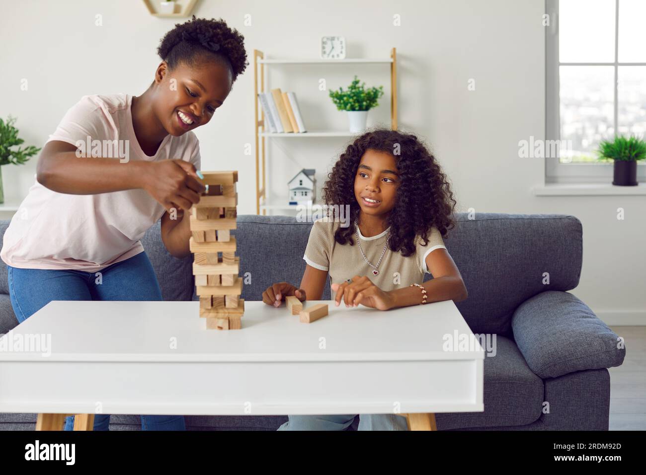 Beautiful happy dark-skinned family playing jenga and having fun at ...