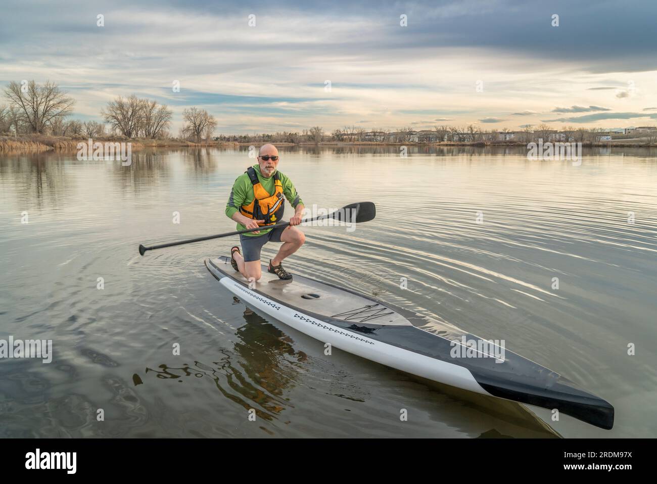 senior man (mid 60s) with a stand up paddleboard is finishing his ...