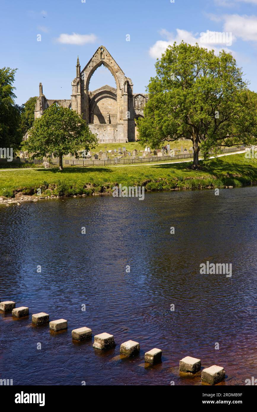 Stepping stones over the River Wharfe with the ruins of Bolton Abbey in ...