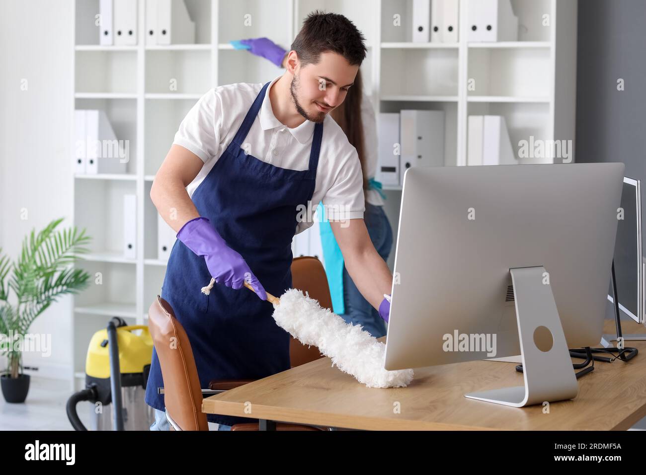 Male janitor cleaning table with pp-duster in office Stock Photo - Alamy