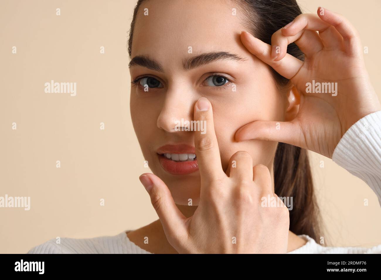 Young woman doing face building exercise on beige background, closeup ...