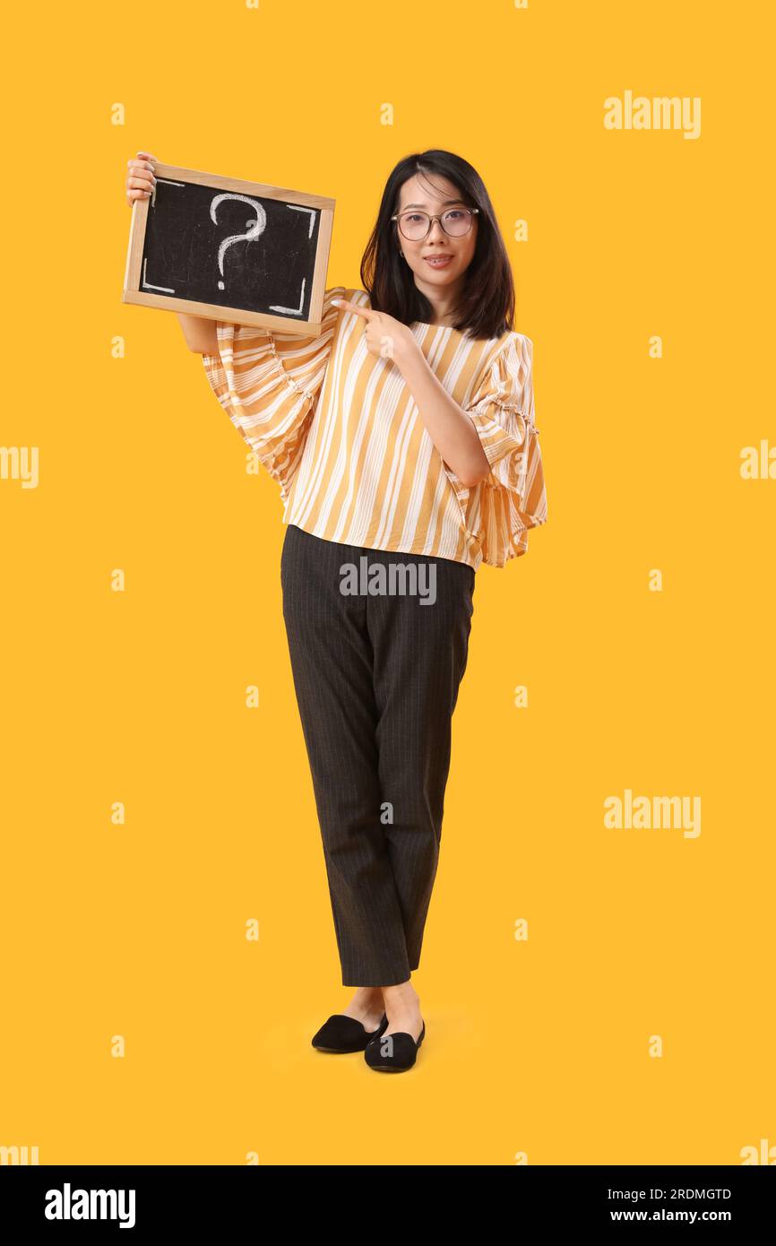 Female Asian teacher pointing at chalkboard with question mark on ...