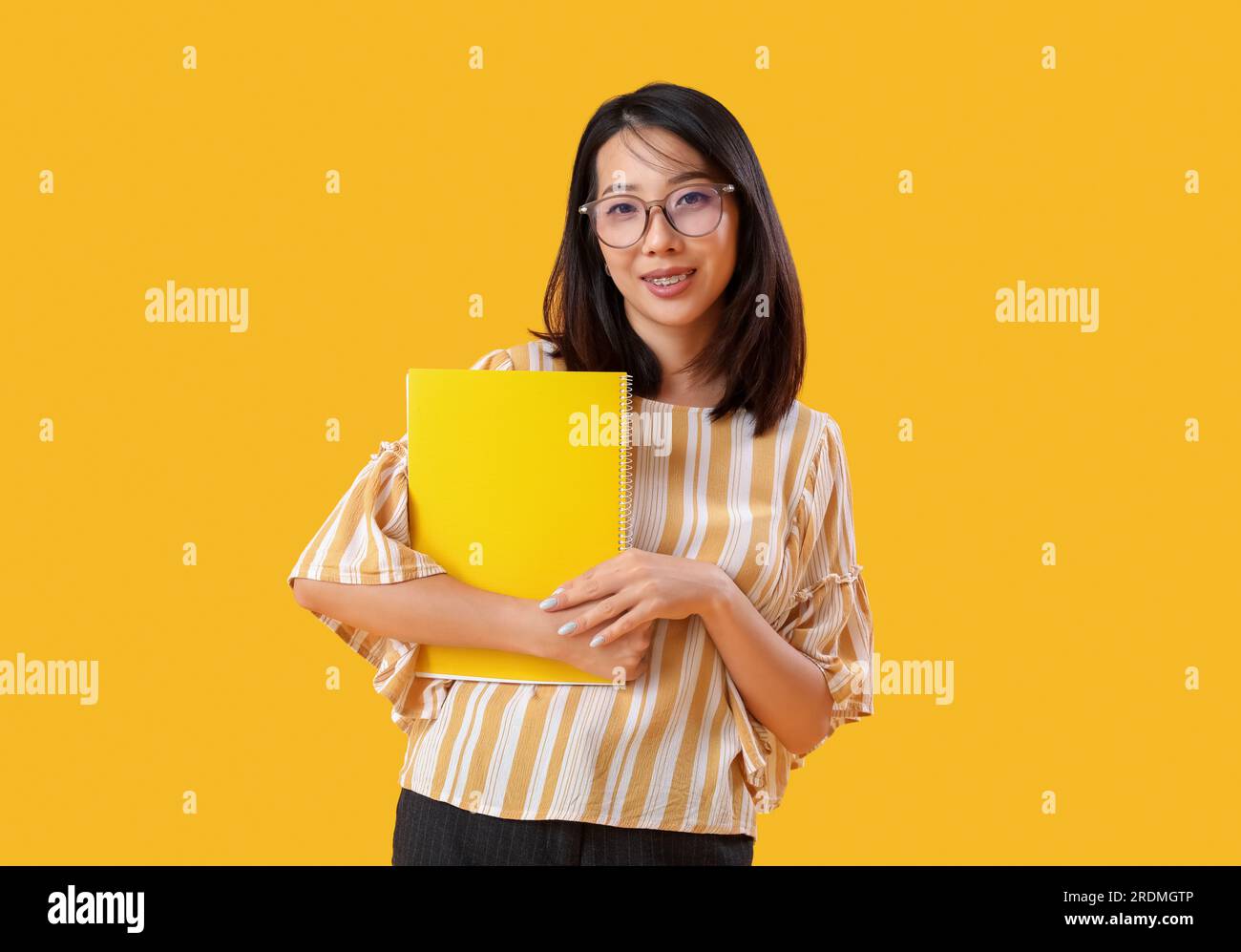 Female Asian teacher with notebook on yellow background Stock Photo - Alamy