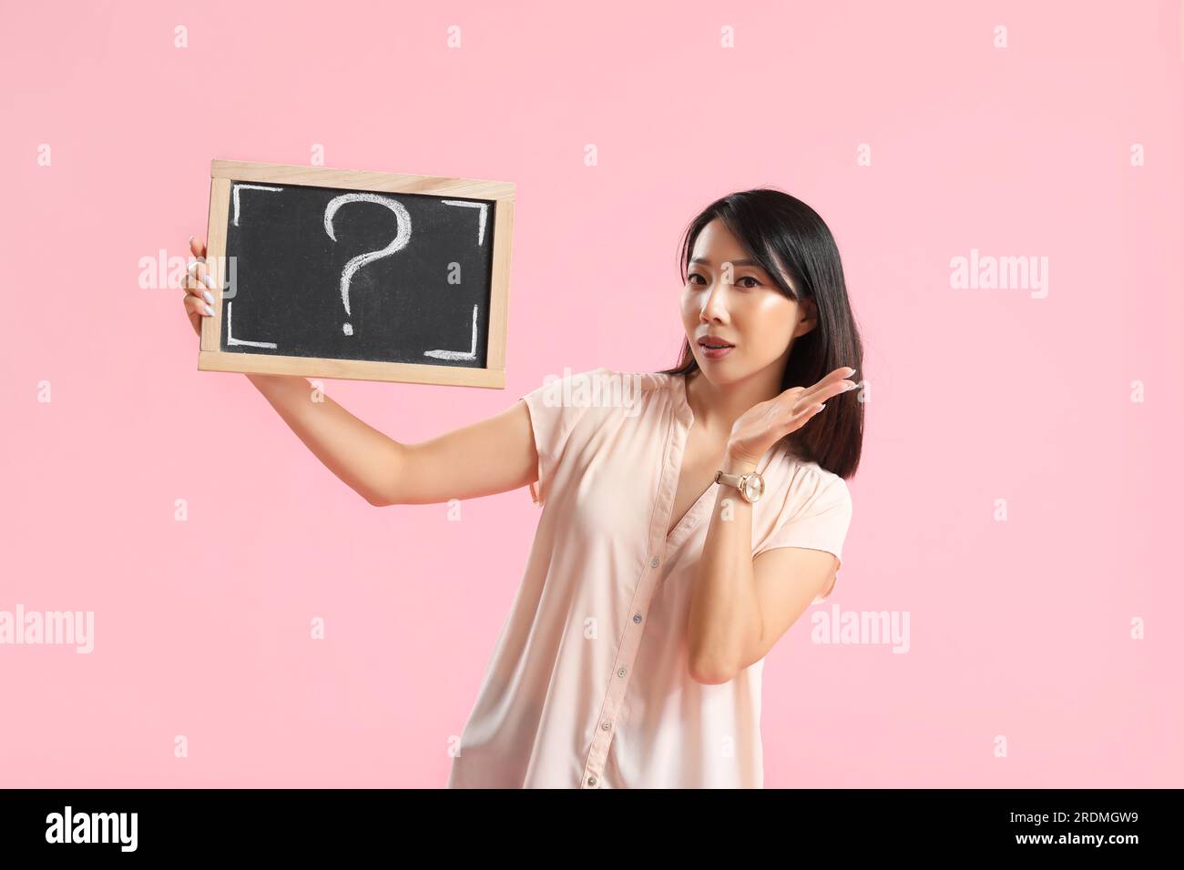 Female Asian teacher holding chalkboard with question mark on pink ...