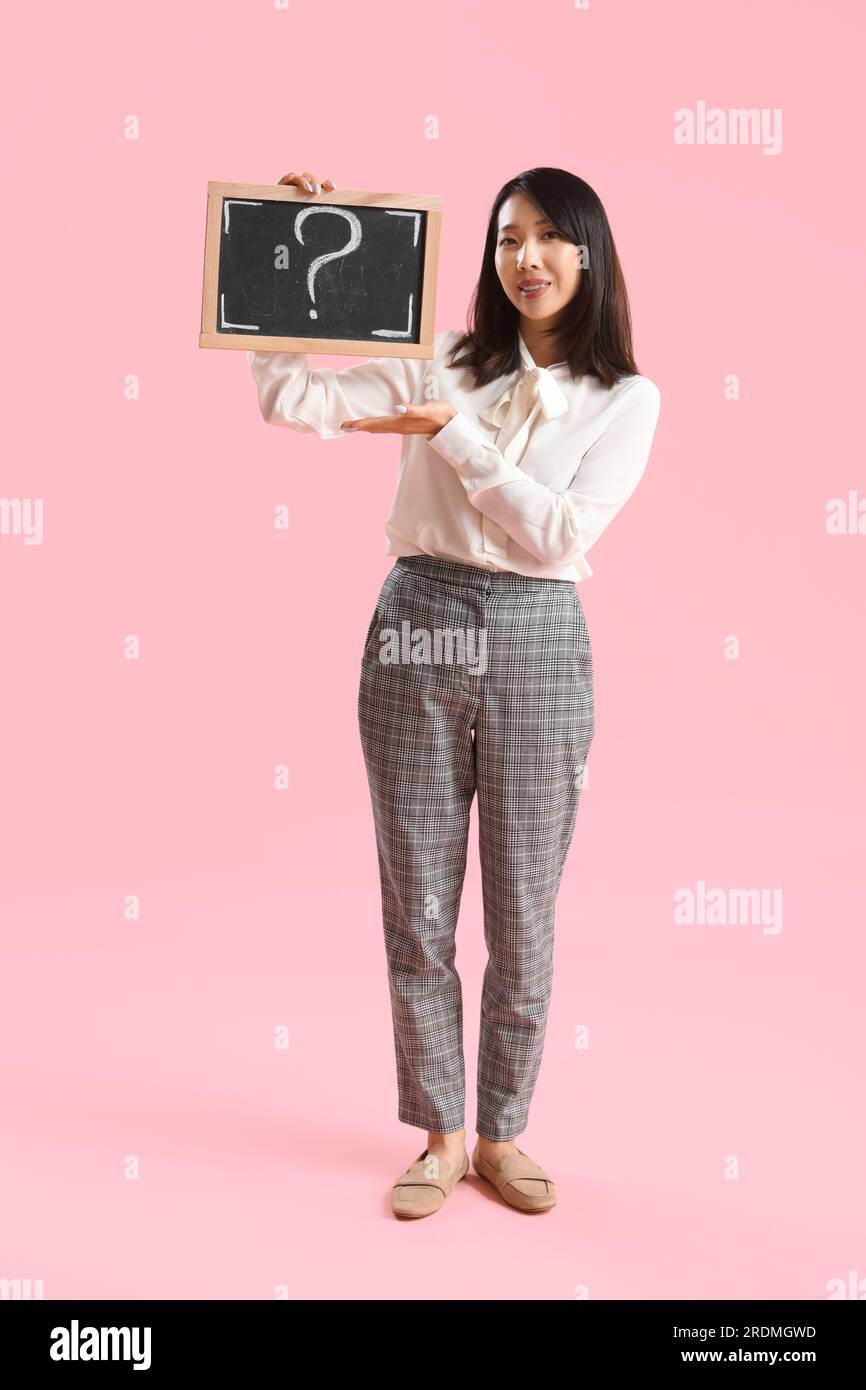 Female Asian teacher holding chalkboard with question mark on pink ...