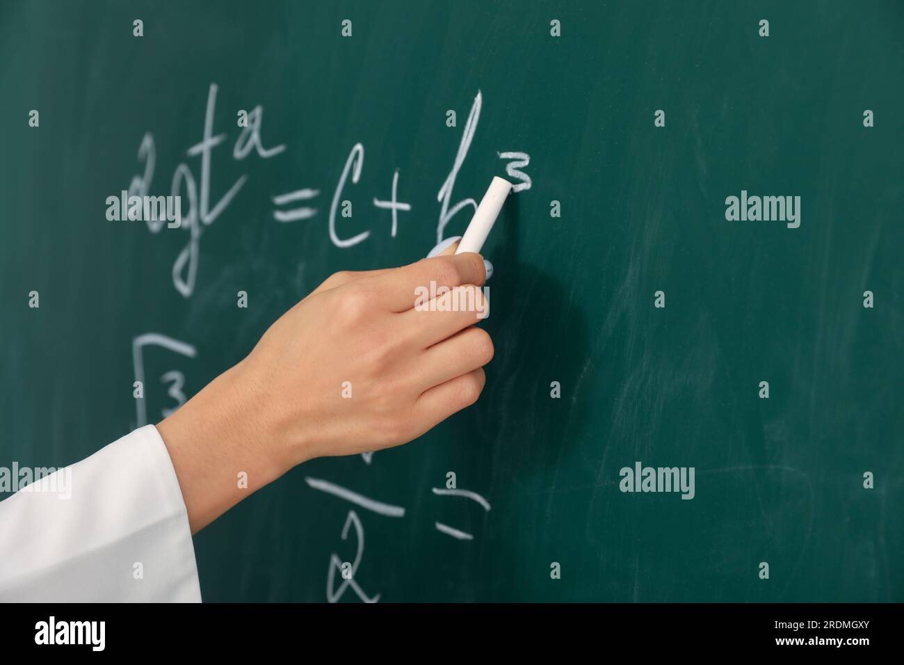 Female teacher writing Math formula on chalkboard in classroom, closeup ...