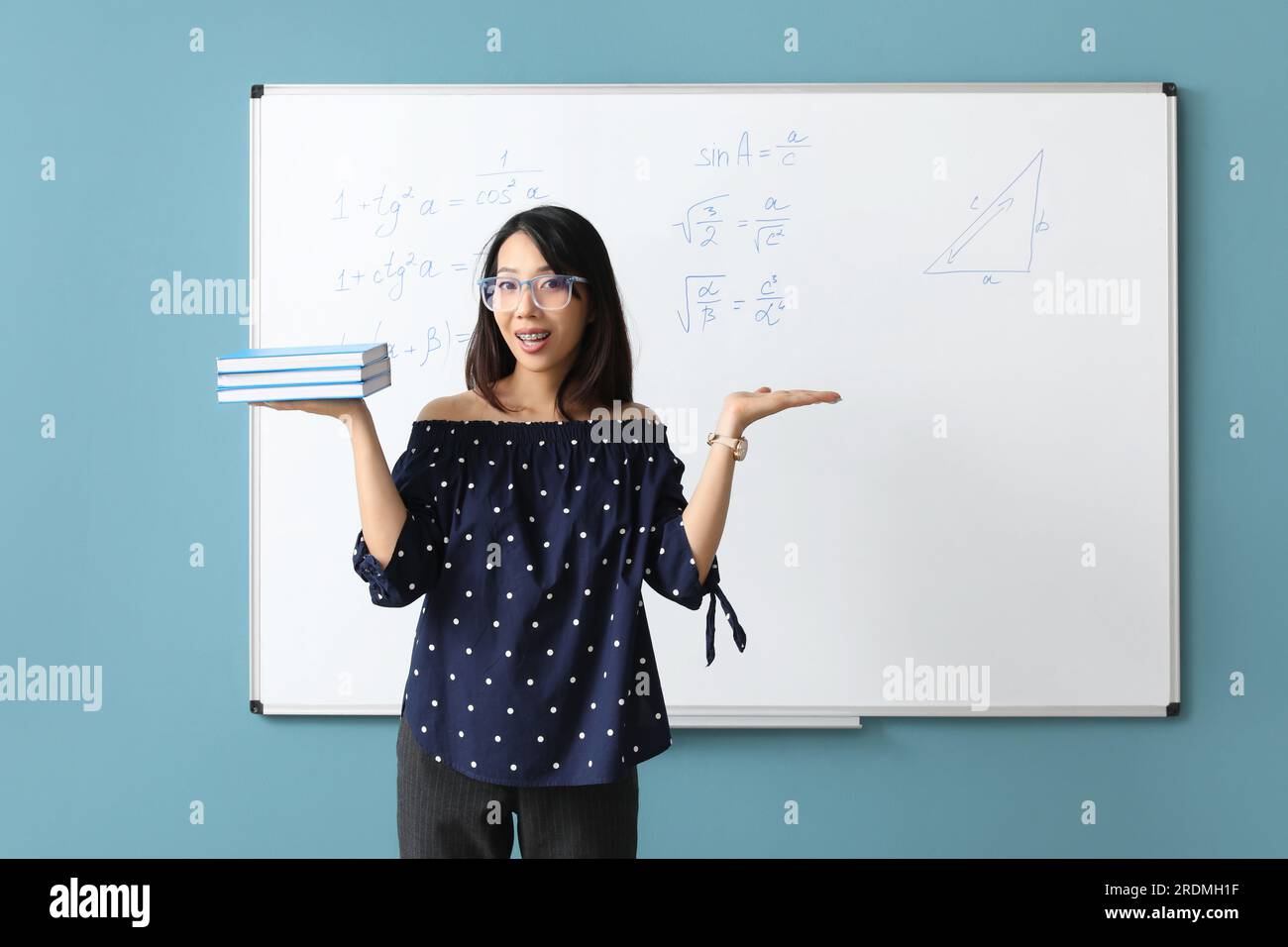 Asian Math teacher with books near flipboard in classroom Stock Photo ...