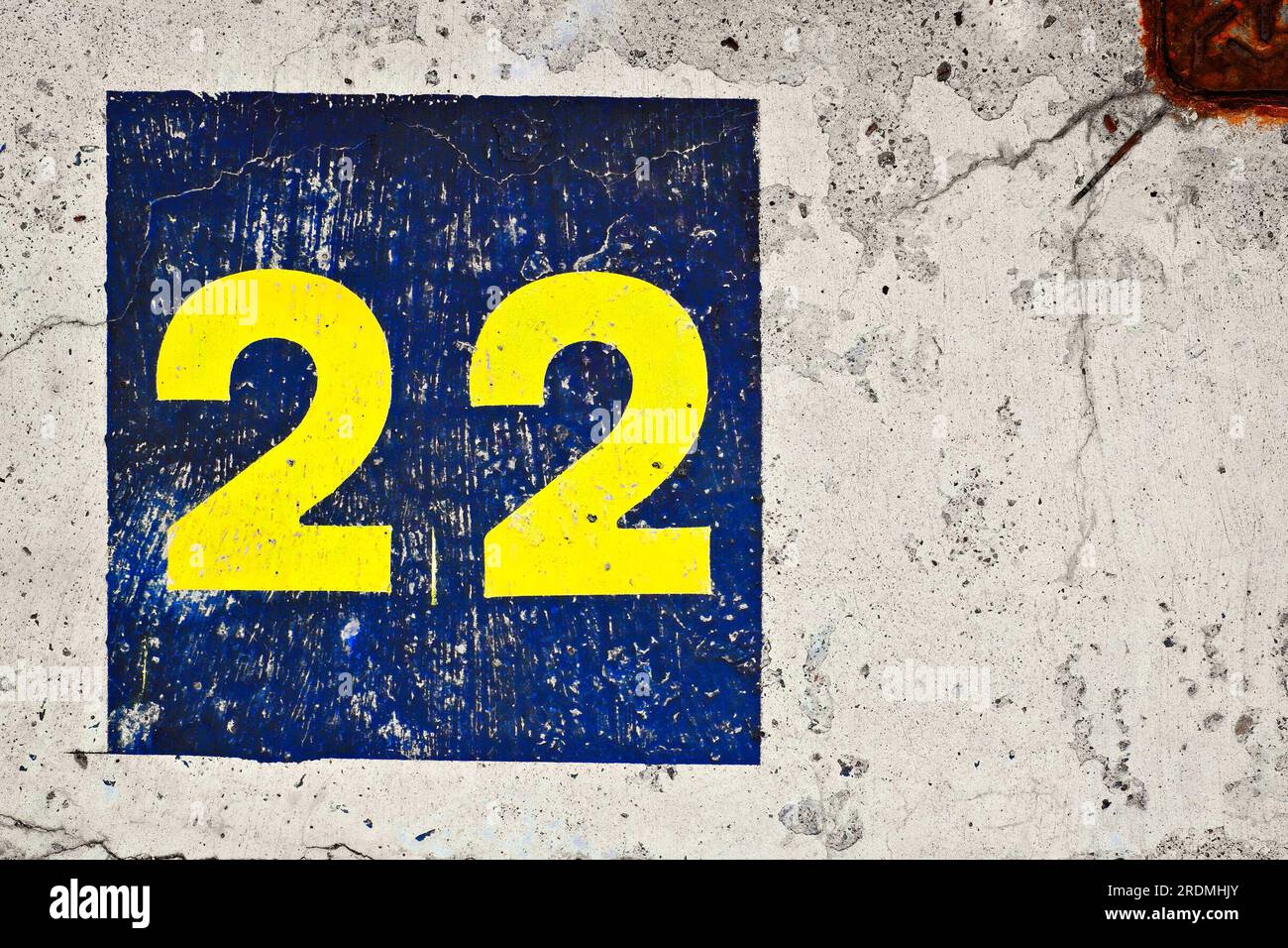 Number 22, twenty-two, painted in yellow and blue on gray concrete ...