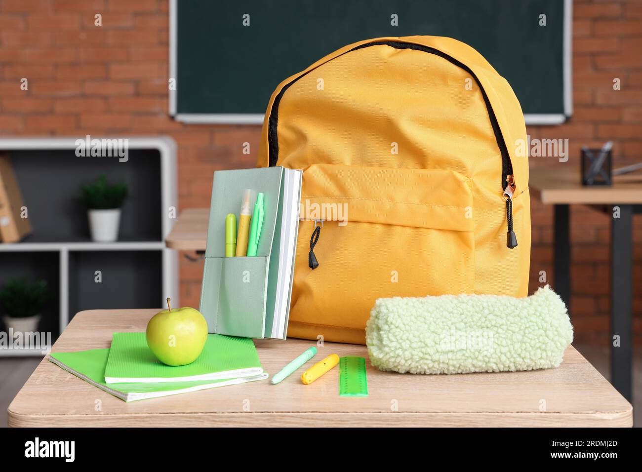 Yellow school backpack with stationery and fresh apple on desk in ...
