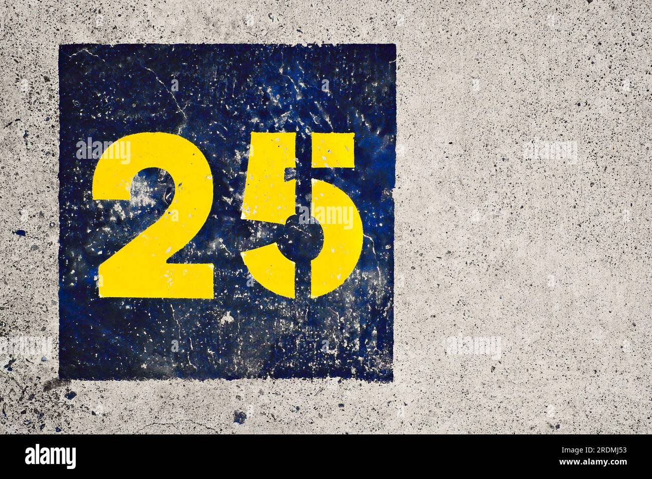 Number 25, twenty-five, blue and yellow stencil painted on gray ...