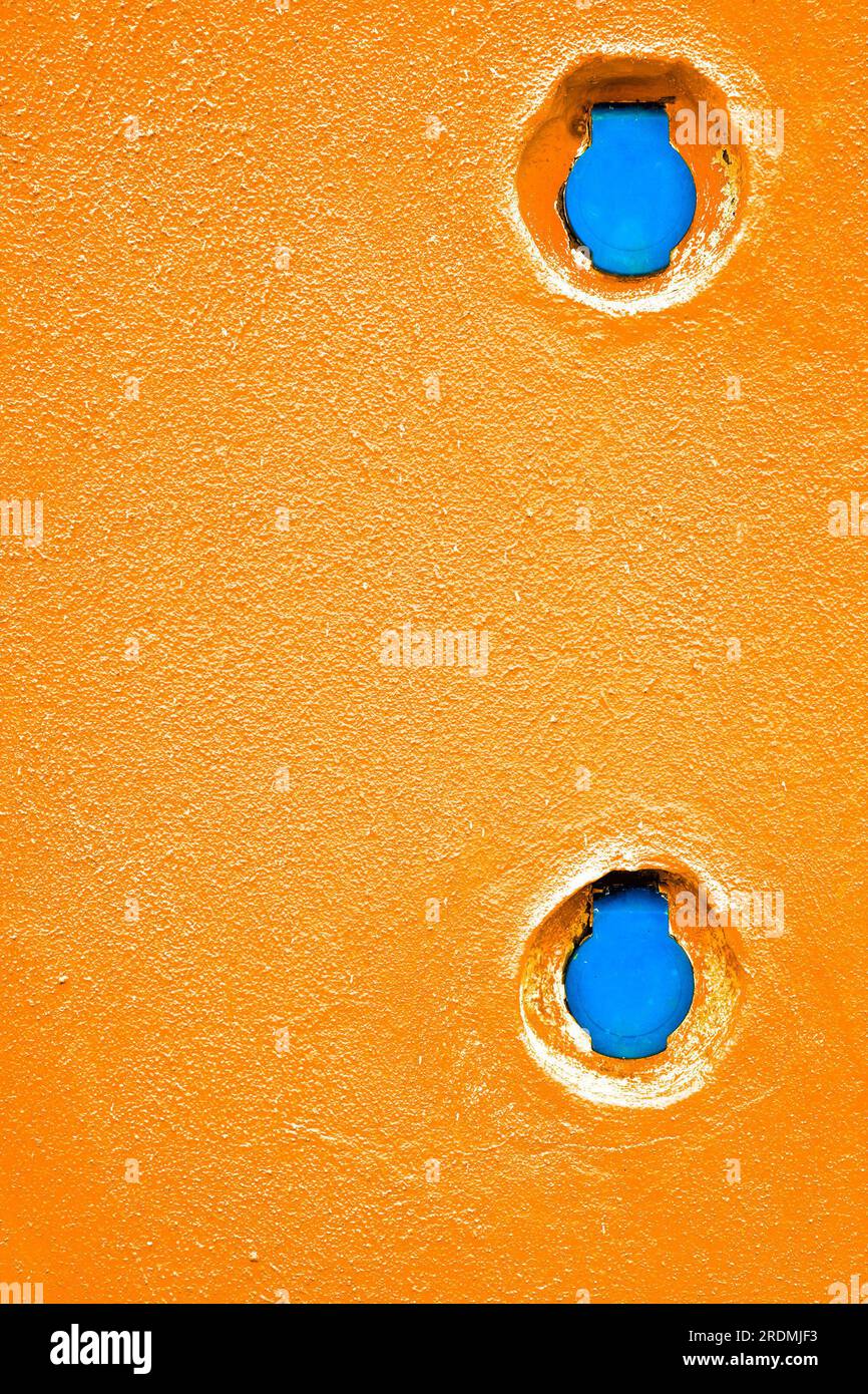Two blue electric sockets in an vibrant orange wall, exterior electric ...