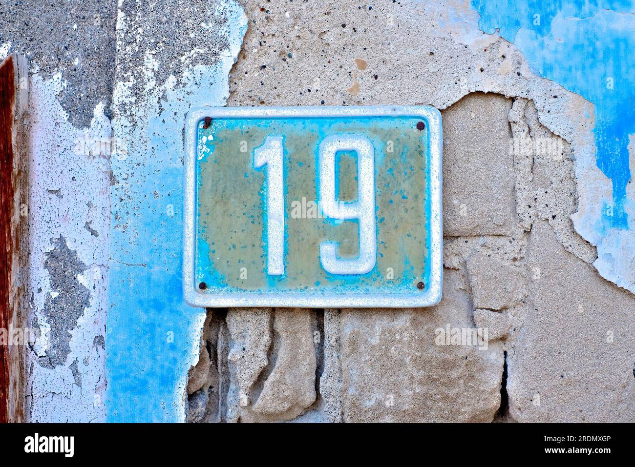 Number 19, nineteen, weathered plate on an old colorful decayed blue ...