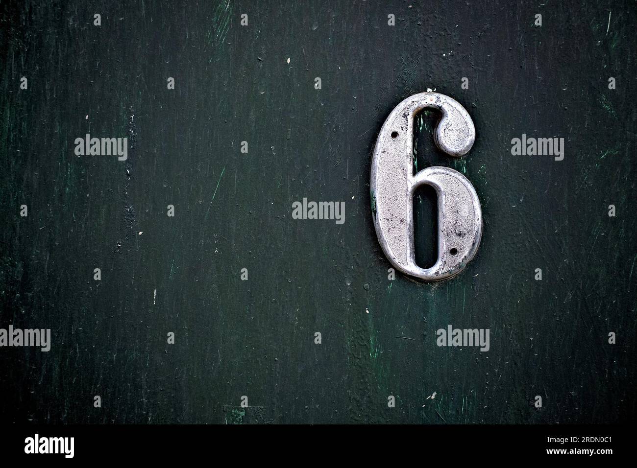 Bold metal number 6, six, on dark subdued background with slight ...